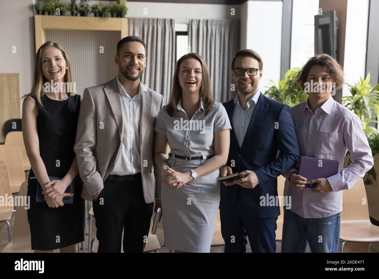 Five employees standing in office posing together for company photo ...