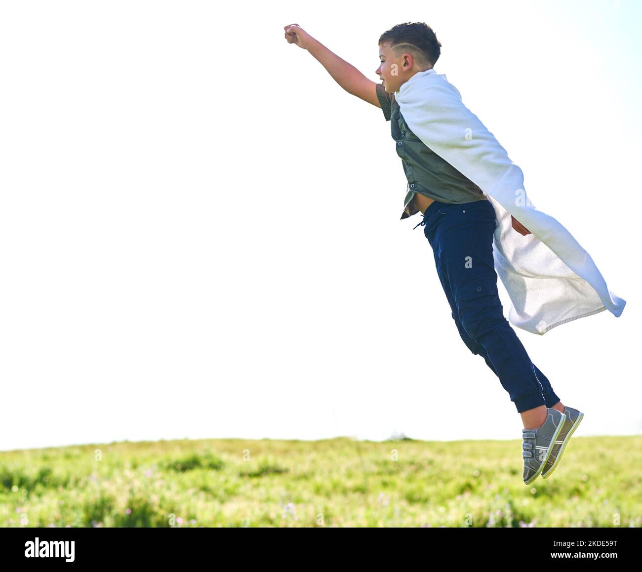 Off to save the day. a cute little boy playing superhero with a cape on ...