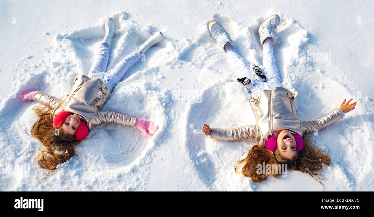 Winter angels. Happy kids girls on make snow angel wings. Two children ...