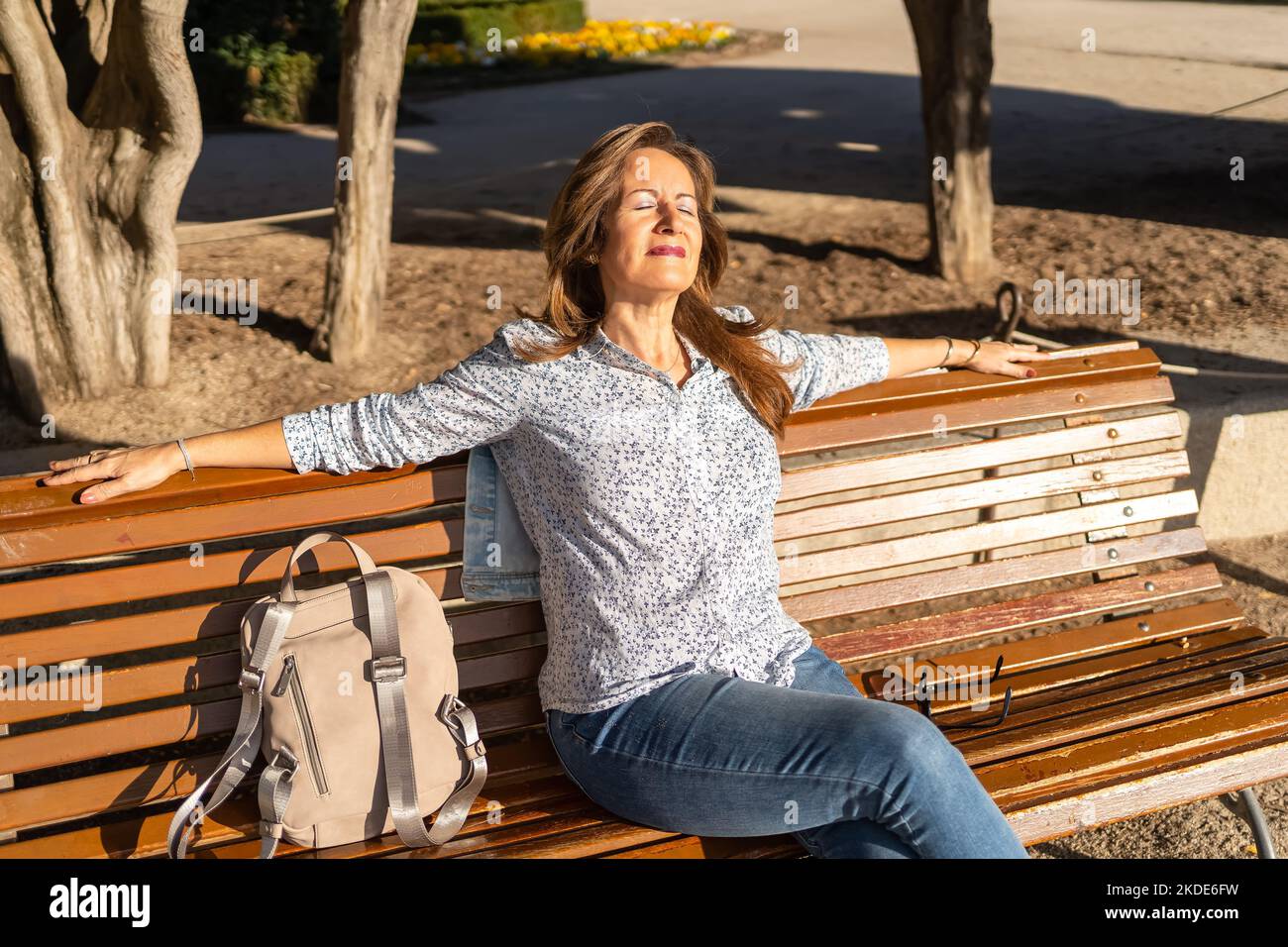 Senior woman sitting on a bench in a public park with her face in the ...