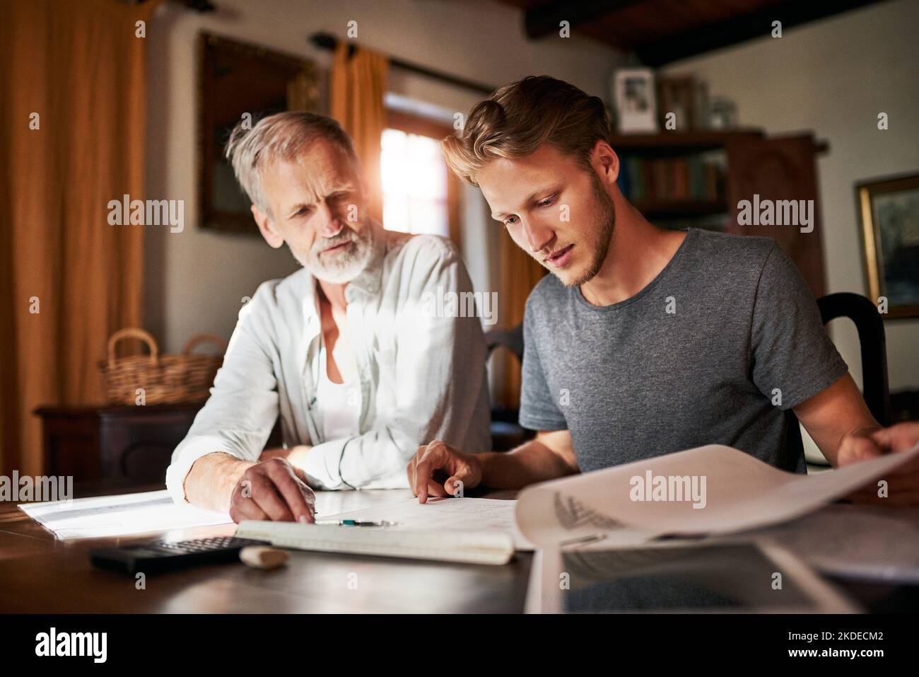 Lets go over it together. two men working on a project together at home ...