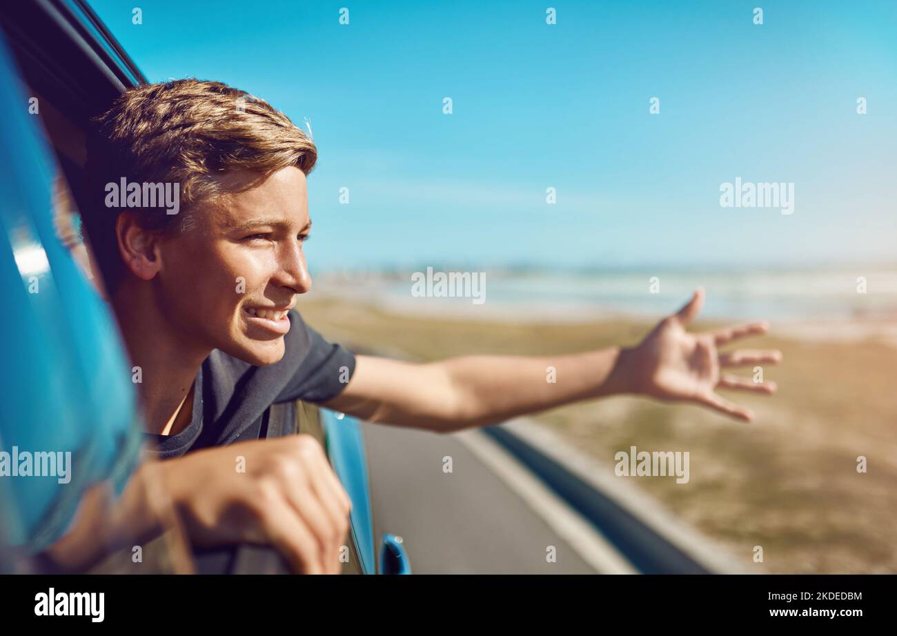 Feel that fresh air. a happy young boy leaning out of the car window on ...