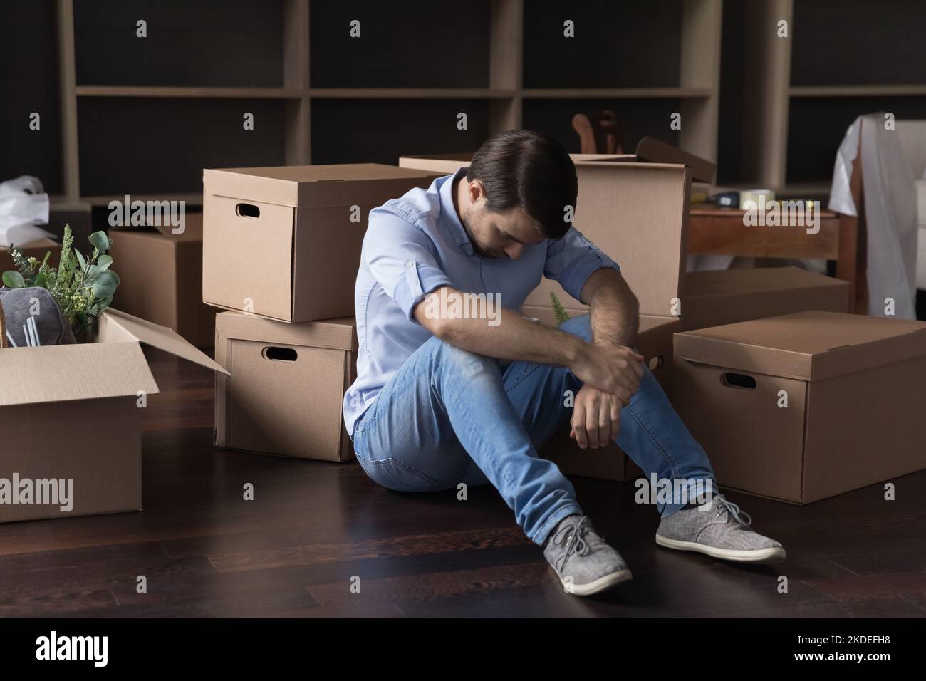 Upset man sit on floor near heap of cardboard boxes Stock Photo - Alamy