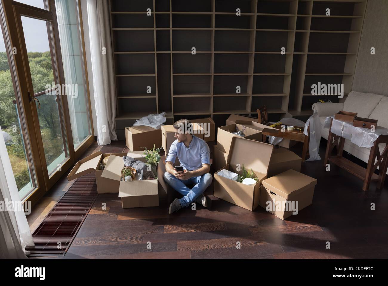 Man sits on floor near boxes with belongings, top view Stock Photo - Alamy
