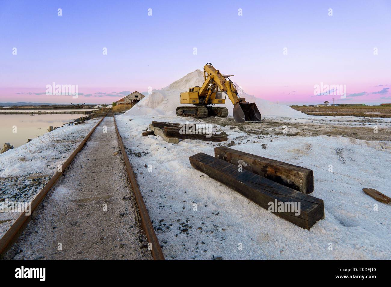 Salt farm excavator with sunset and a salt mountain Stock Photo - Alamy