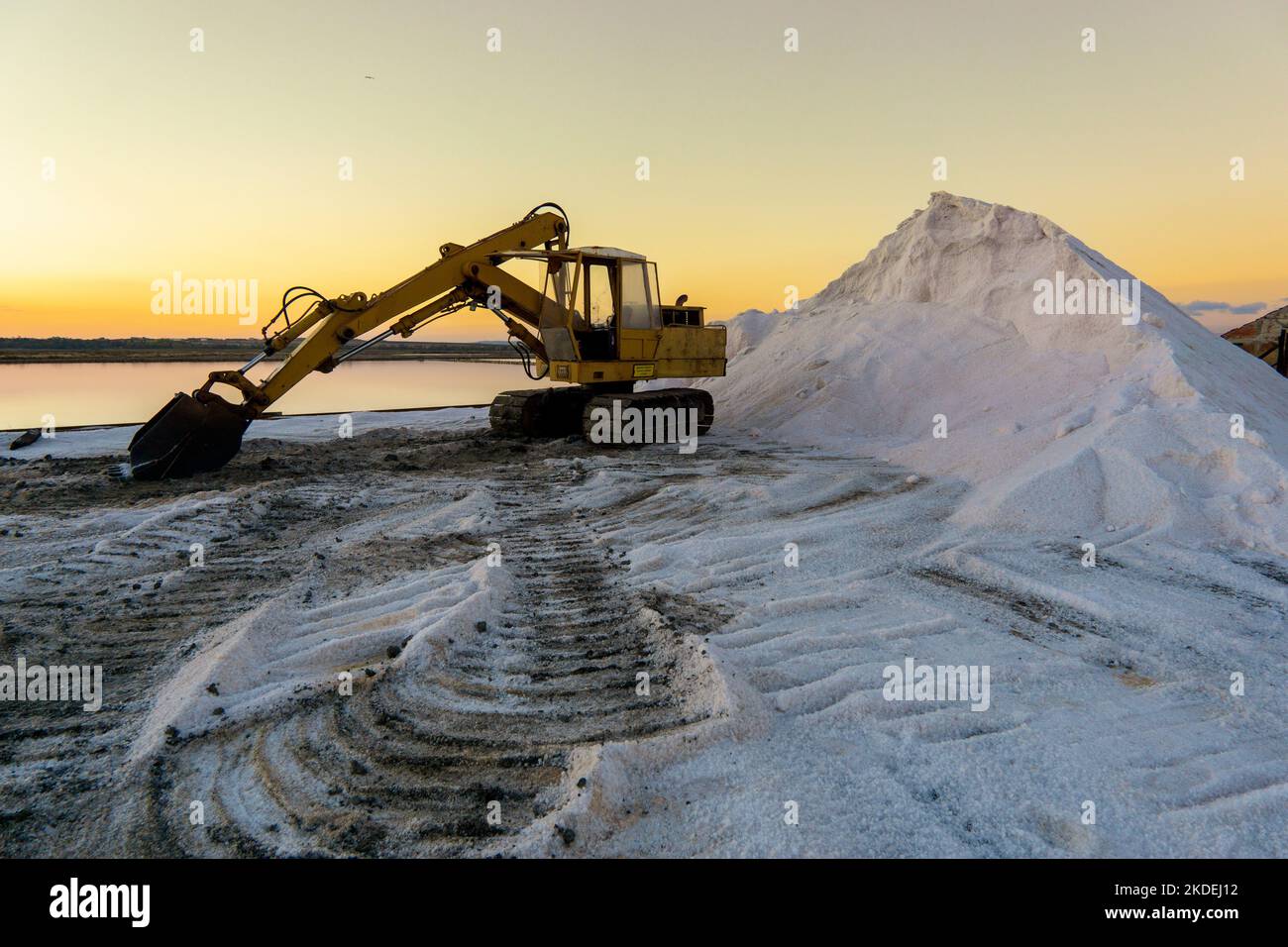 Salt farm excavator with sunset and a salt mountain Stock Photo - Alamy