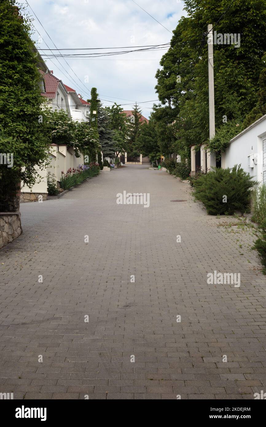 A picturesque alley in a modern suburb. The roadway is paved with ...