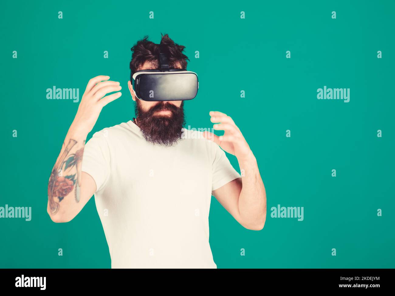 Man with beard in VR glasses, green background. Hipster on busy face ...