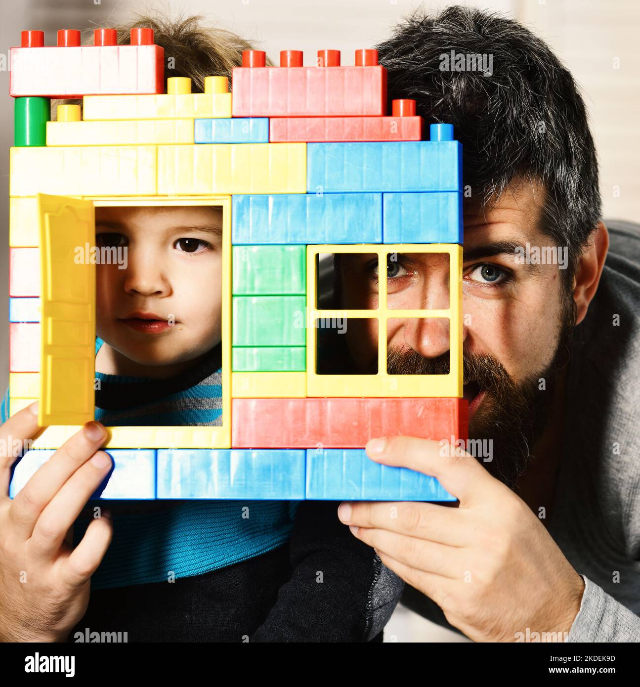 Father and son with calm faces behind colorful bricks construction ...