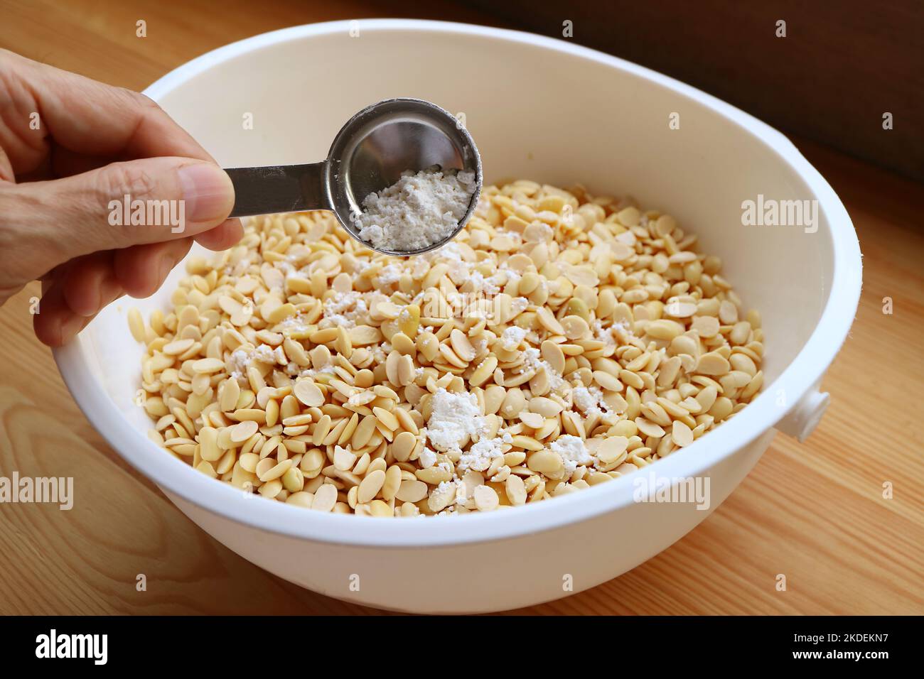 Hand Putting a Spoon of Tempeh Starter into Boiled Soybeans Bowl before ...