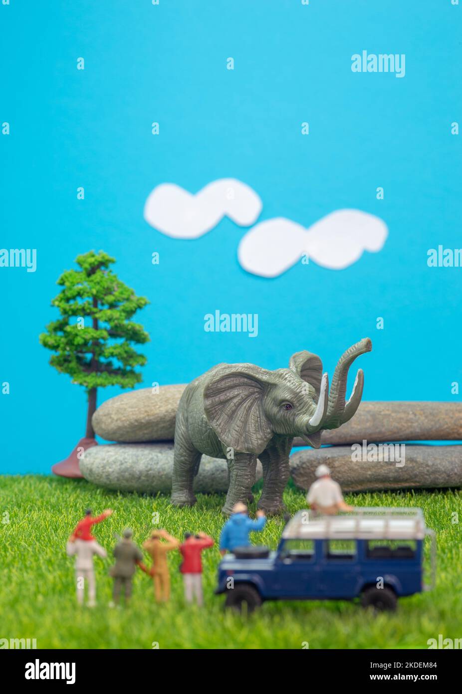 Miniature toys of a group of people on safari trip watching loxodonta ...
