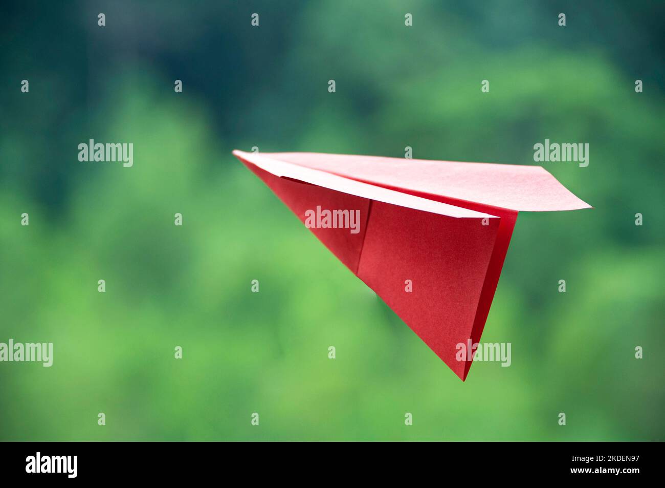 Flying red paper plane with blurred green nature background Stock Photo ...