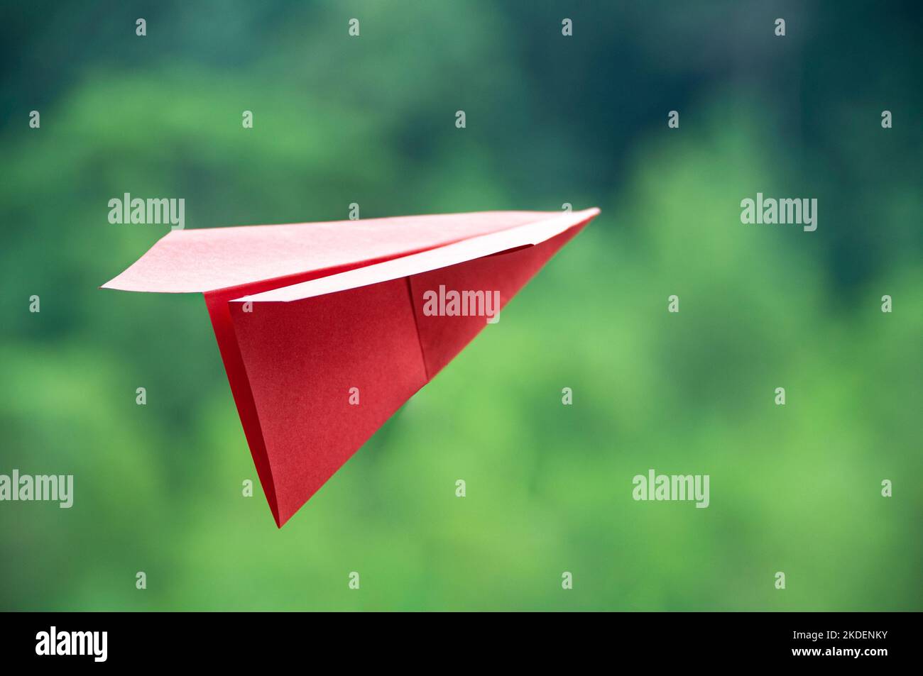 Flying red paper plane with blurred nature background. Travelling ...