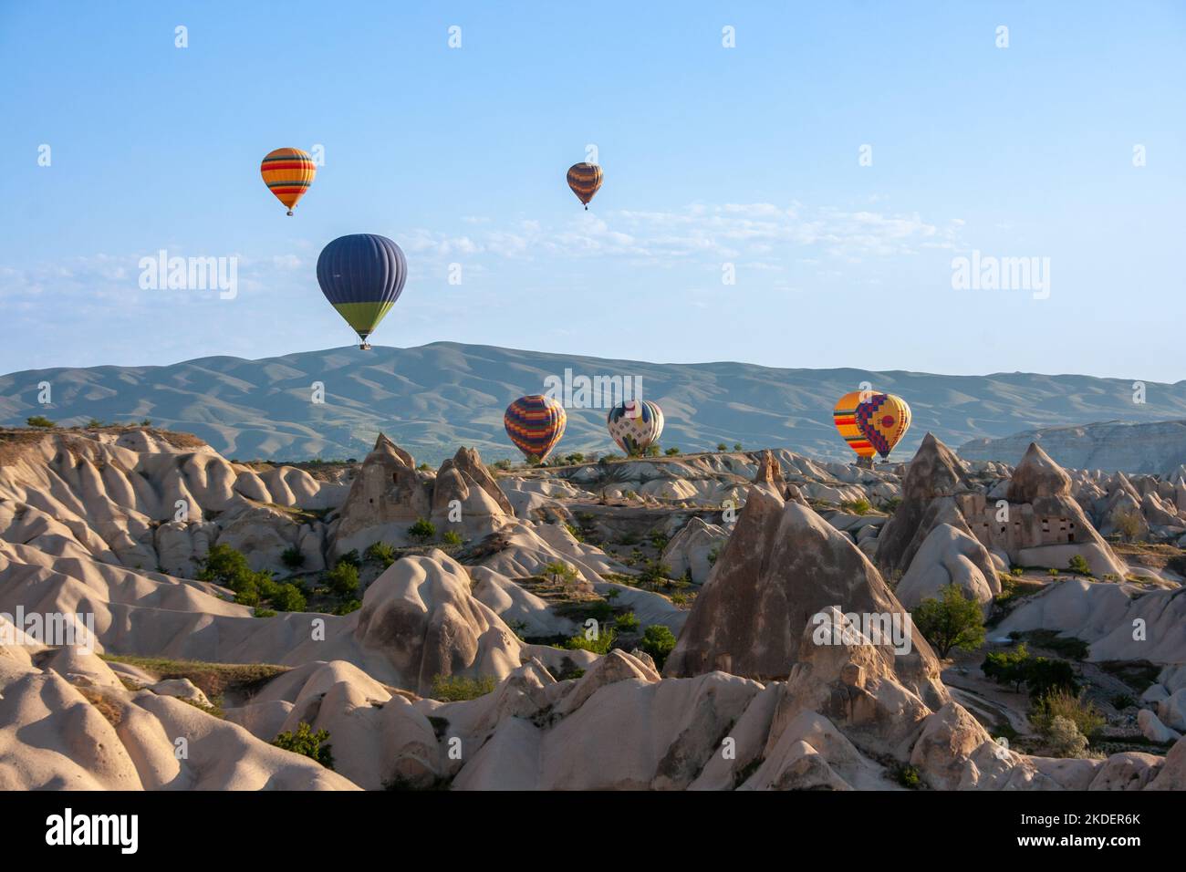 hot air balloons rise over the chimneys rock formation, Cappadocia ...