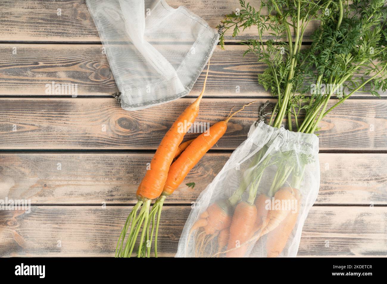 Bunch of fresh ripe carrots with long green haulm on faded wooden table ...