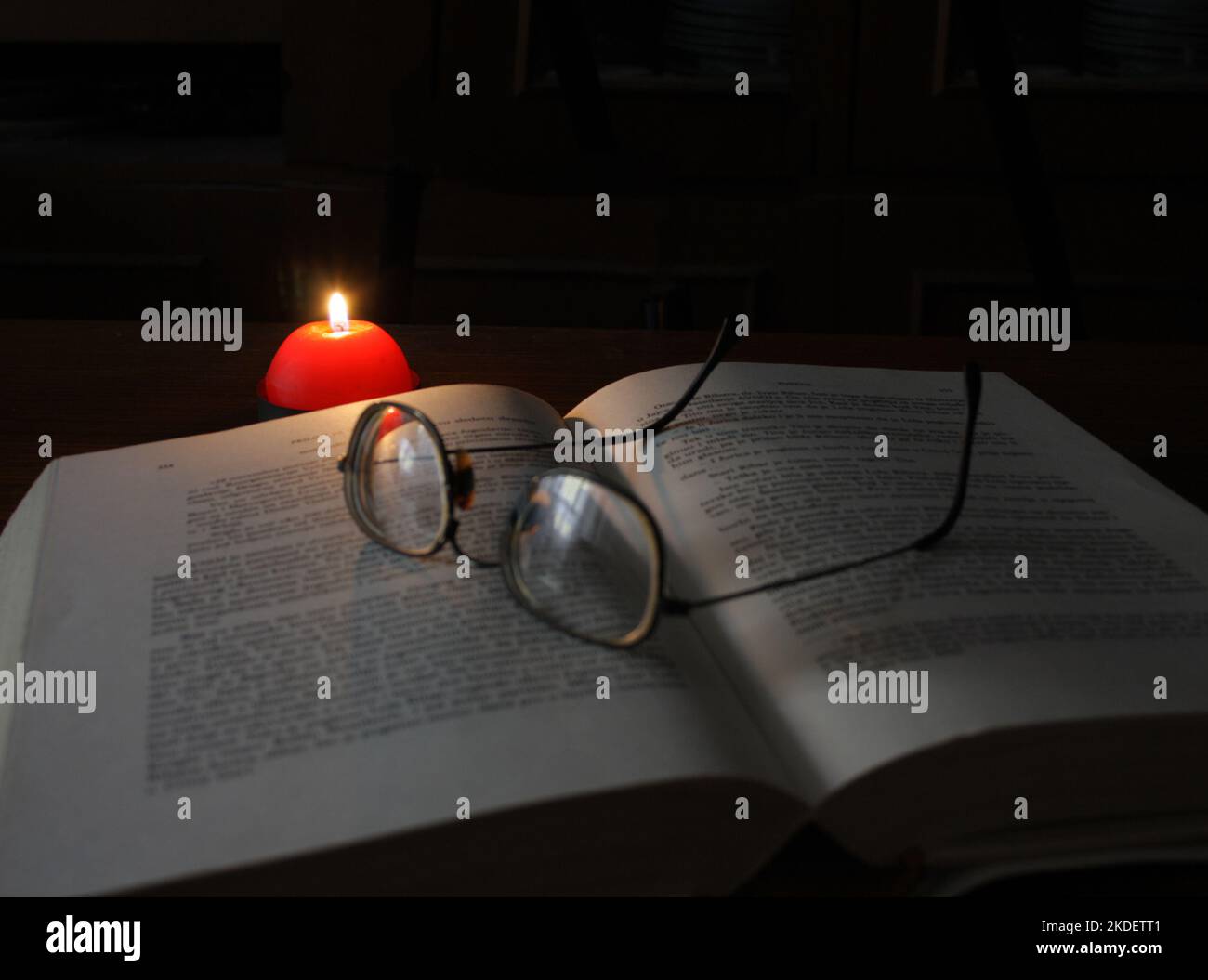 An open book and glasses on it, under a candlelight Stock Photo - Alamy