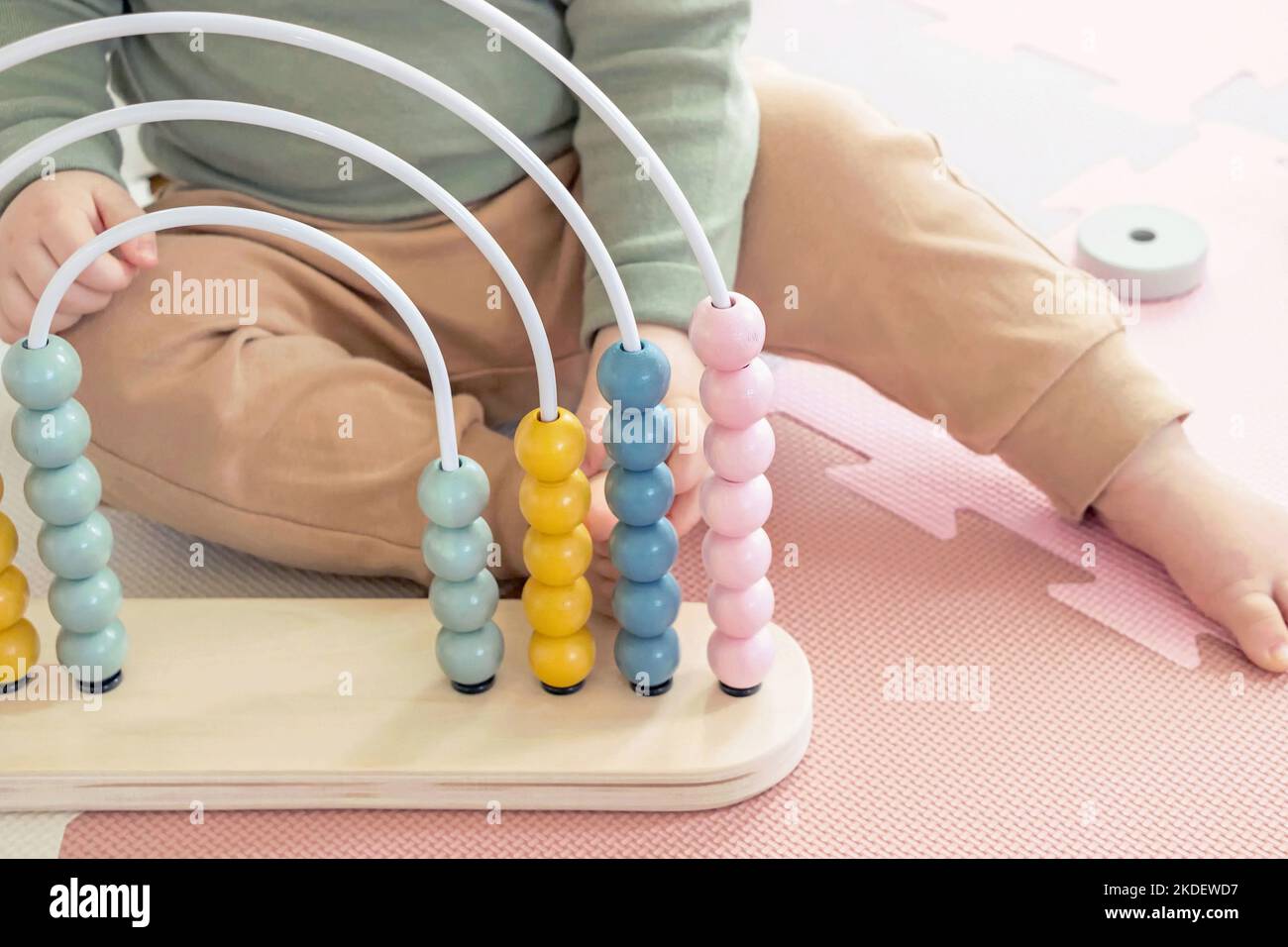 close up of one year toddler baby sitting on carpet playing with wooden ...