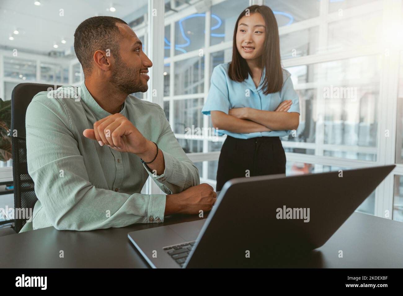 Two multiethnic colleagues talking while working together in modern ...