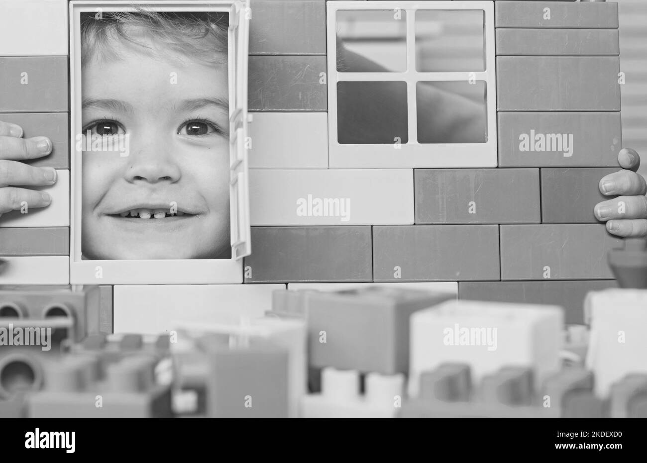 Child plays with construction bricks, looking through door of toy Stock ...