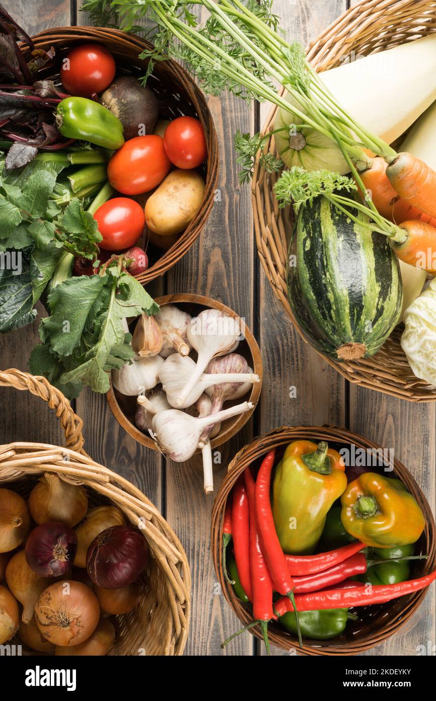Wicker baskets with different fresh garden vegetables on wooden table ...