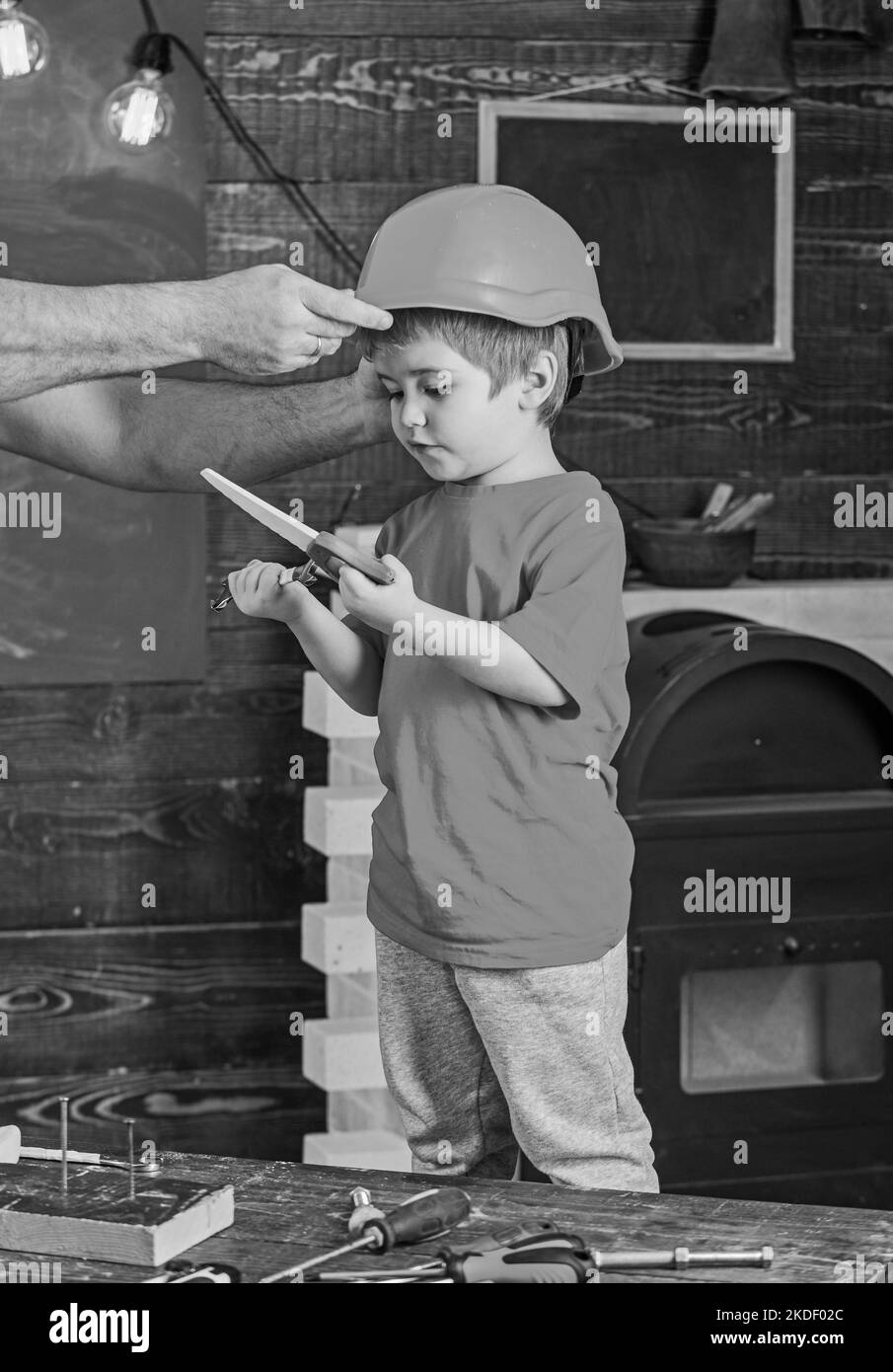 Boy standing behind the table with various tools. Daddy taking care ...