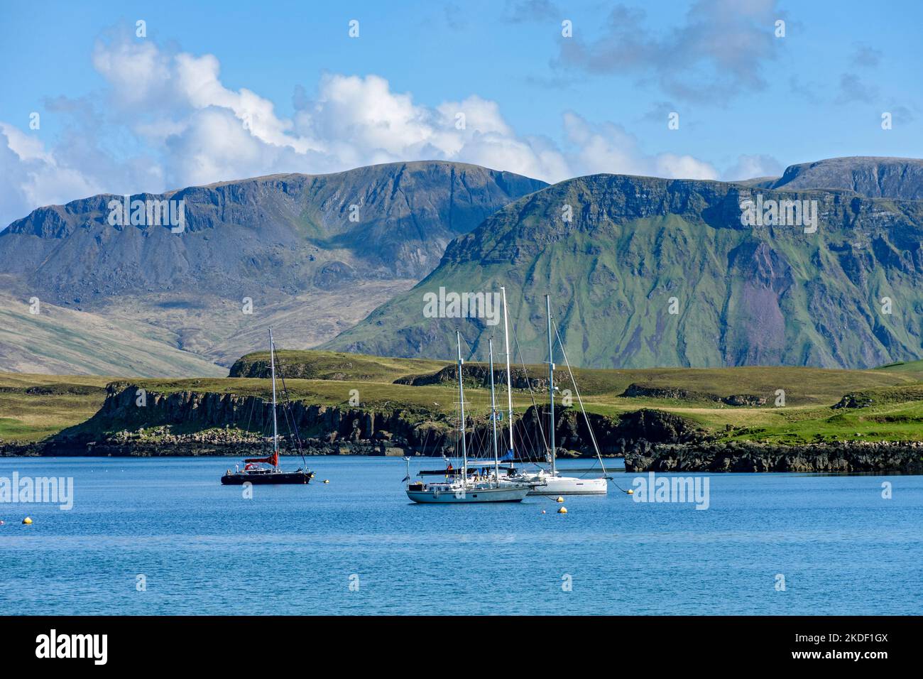 Boats moored in Canna Harbour with the islands of Sanday and Rum behind ...