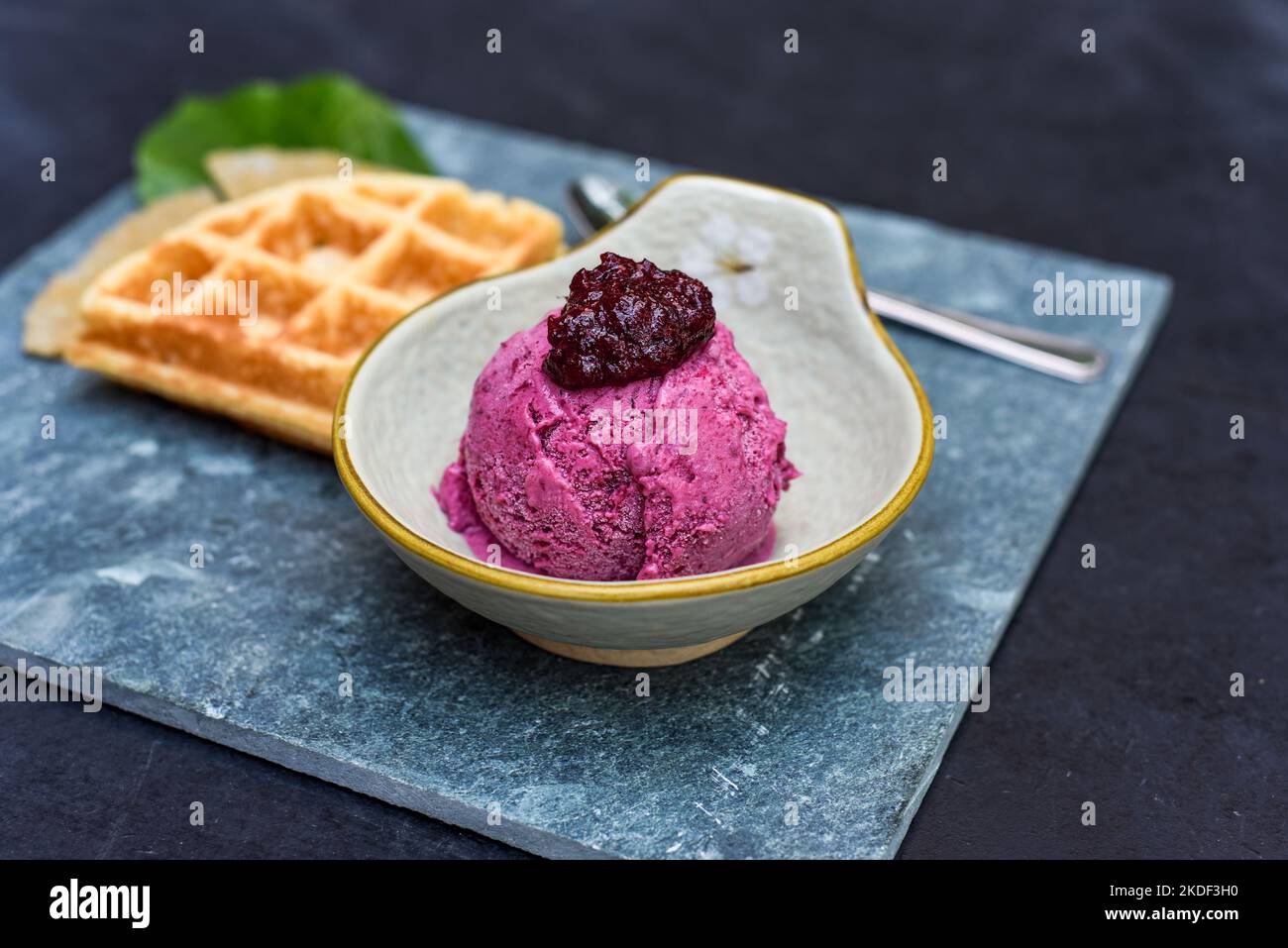 Hibiscus organic ice cream with waffle on stone plate with spoon and ...