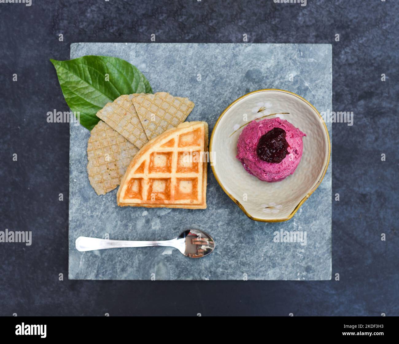 Hibiscus organic ice cream with waffle on stone plate with spoon and ...