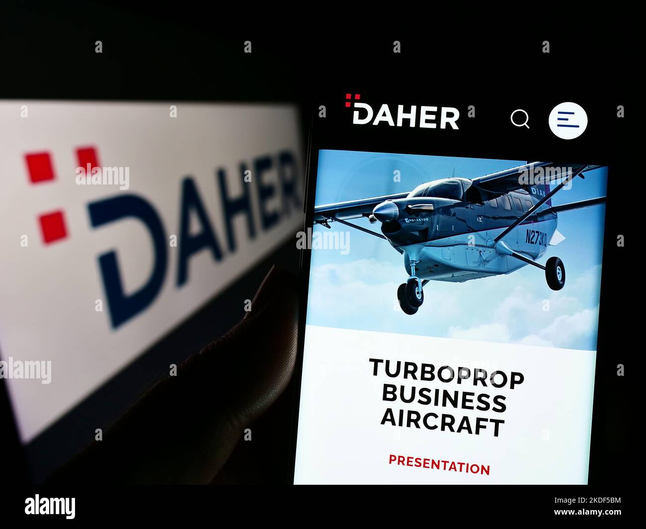 Person holding cellphone with website of French aerospace company Daher ...