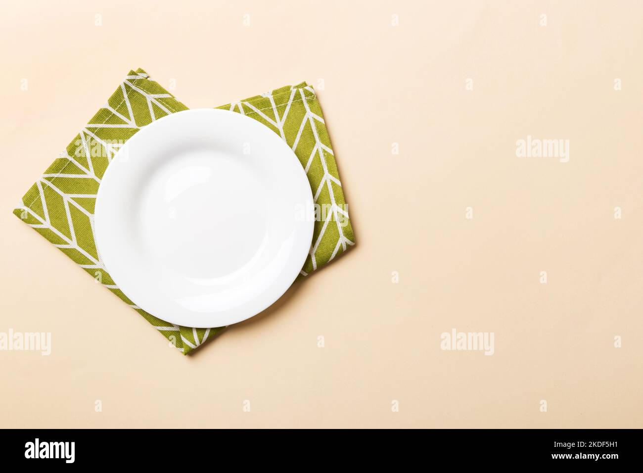 Top view on colored background empty round white plate on tablecloth ...