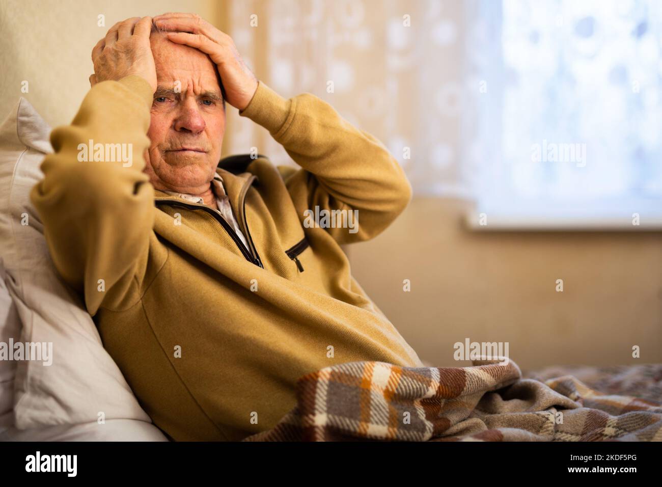 old man winces with headache due to noise Stock Photo - Alamy