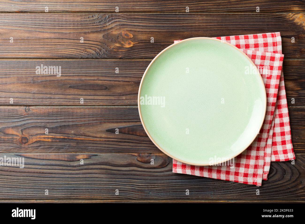 Top view on colored background empty round green plate on tablecloth ...