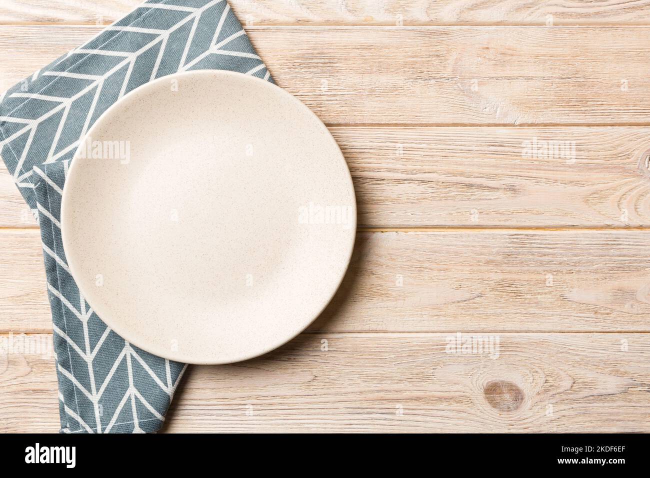 Top view on colored background empty round white plate on tablecloth ...