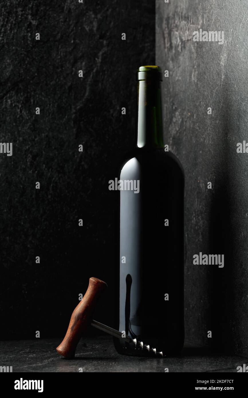 Bottle of red wine and corkscrew on a black stone background Stock ...