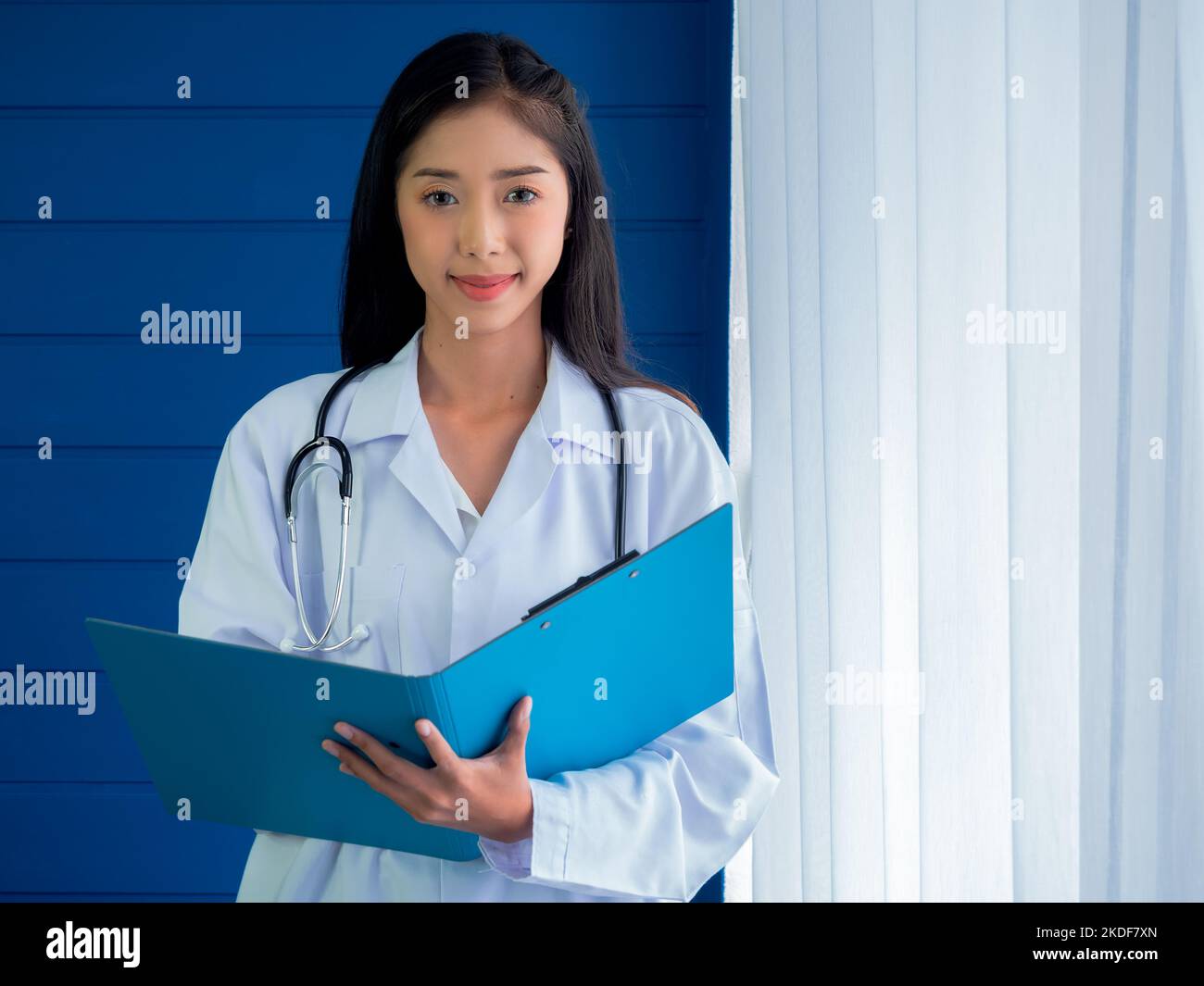 Smiling pretty Asian woman doctor portrait standing on blue wood and ...