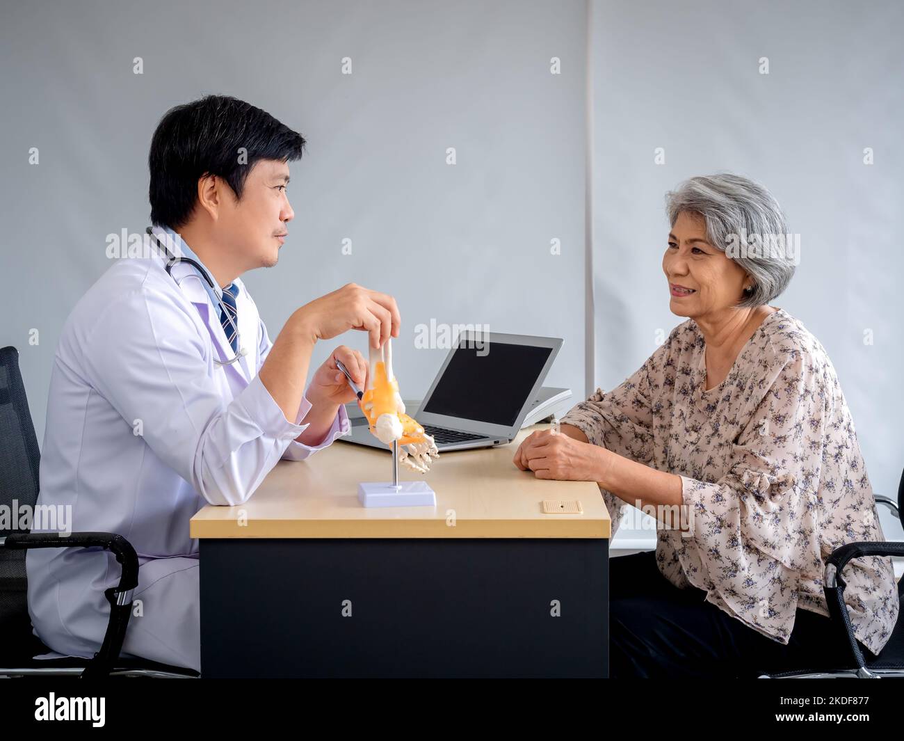 Smiling professional Asian man orthopedic doctor pointing to foot ...