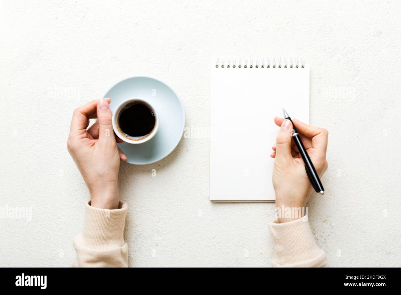 Woman hand with pencil writing on notebook and hold coffee cup. Woman ...