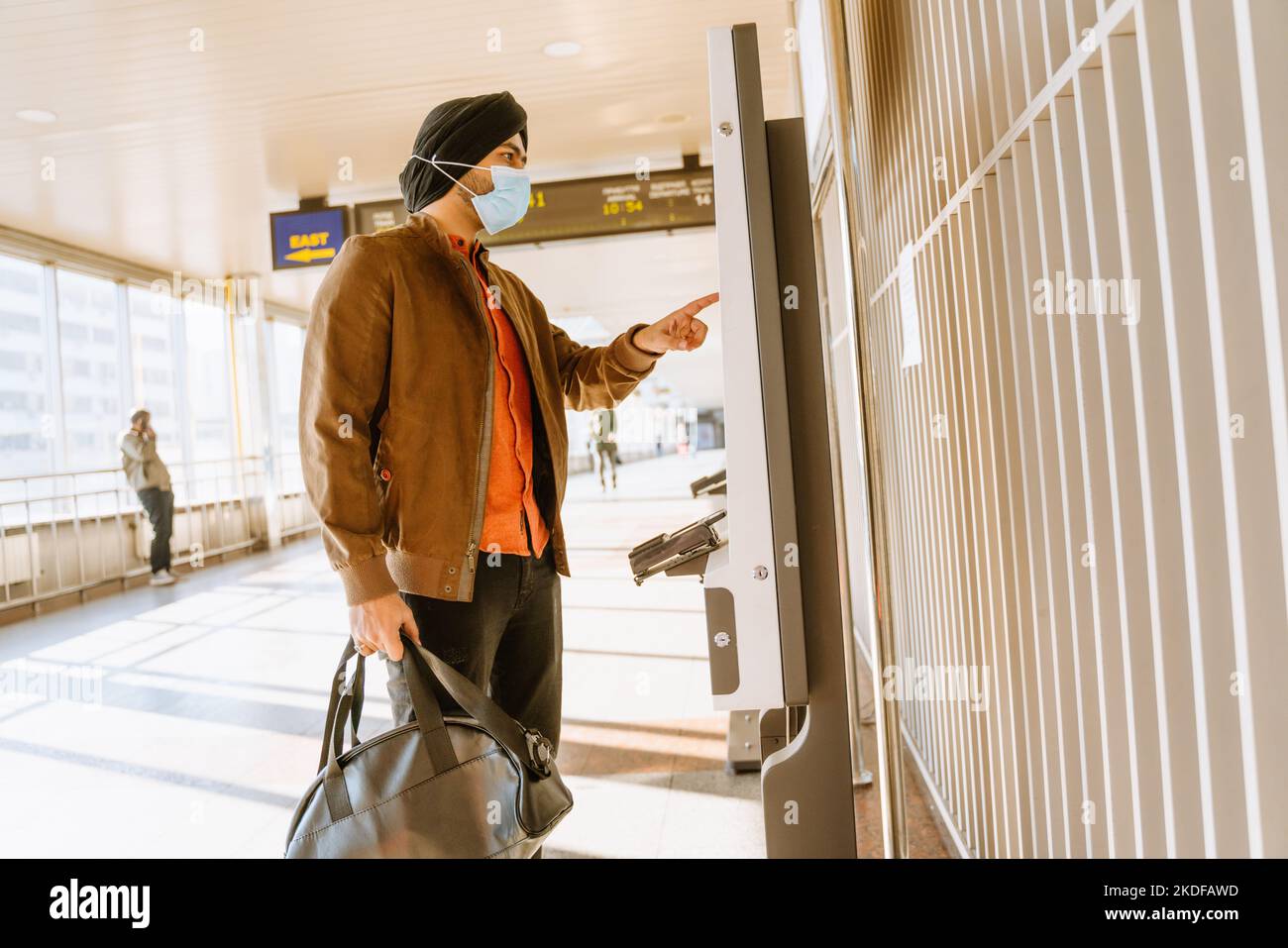 Indian man wearing face mask buying ticket at train station indoors ...