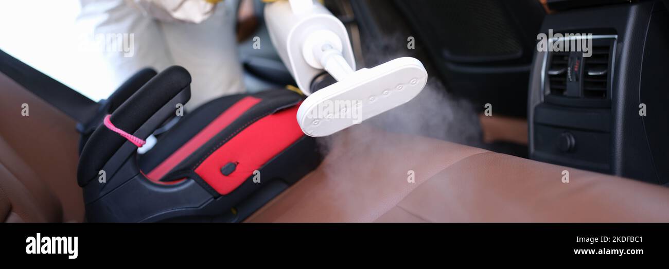 Worker in uniform cleanse car interior using steam cleaner with spray ...