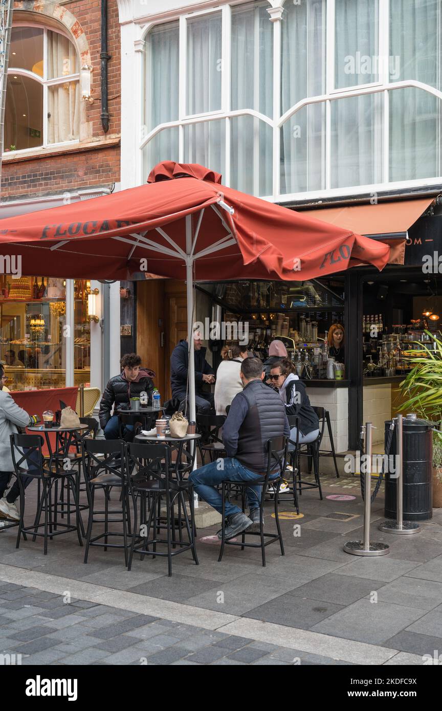 People seated at pavement tables enjoying refreshments at Flocafe ...