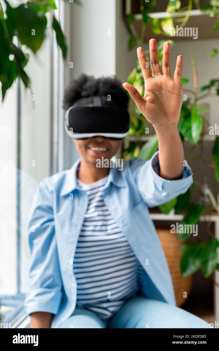 African woman in VR helmet interacting with objects in virtual world ...
