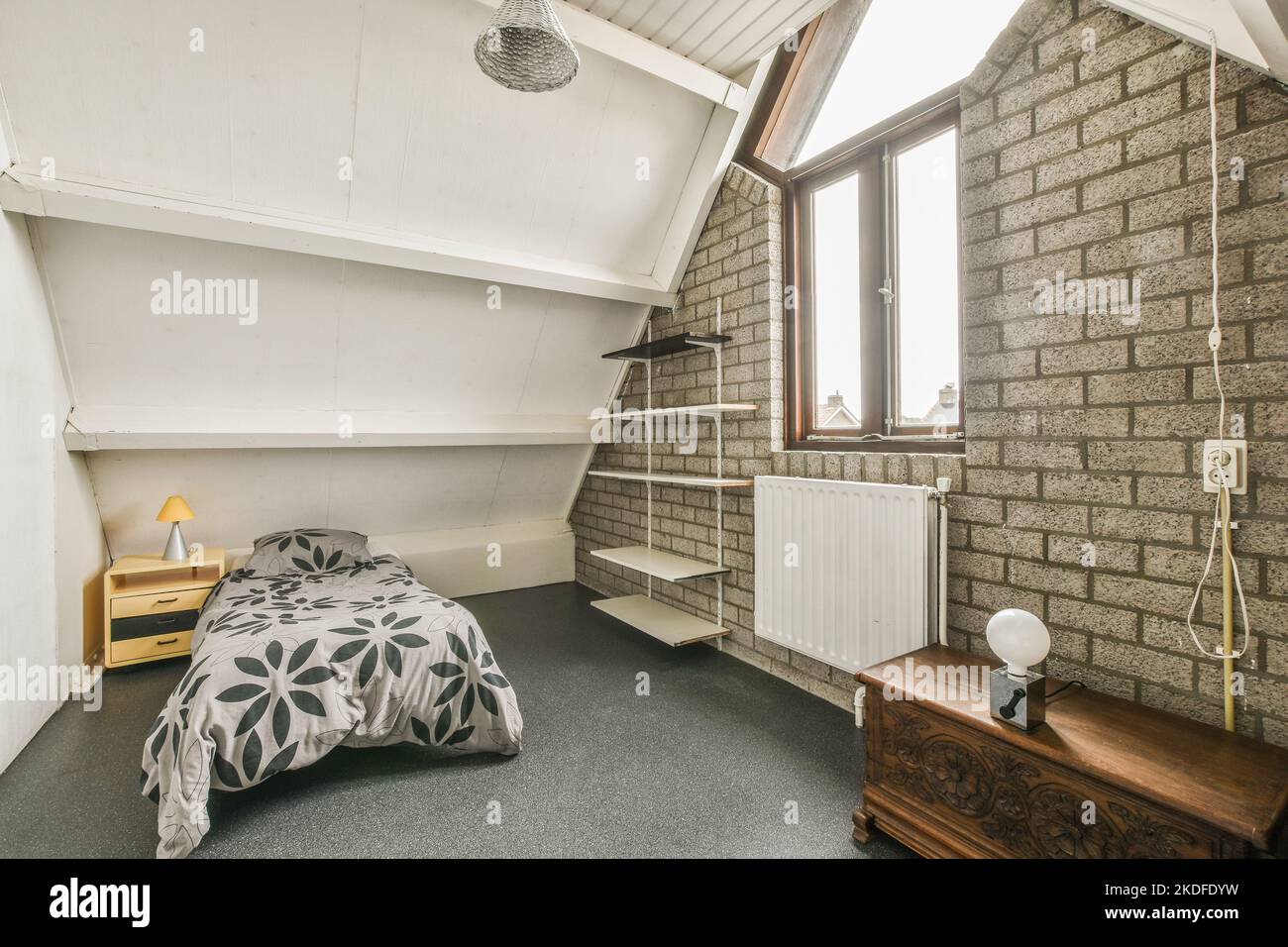 Comfortable bed with white bedclothes and bedside table placed near ...