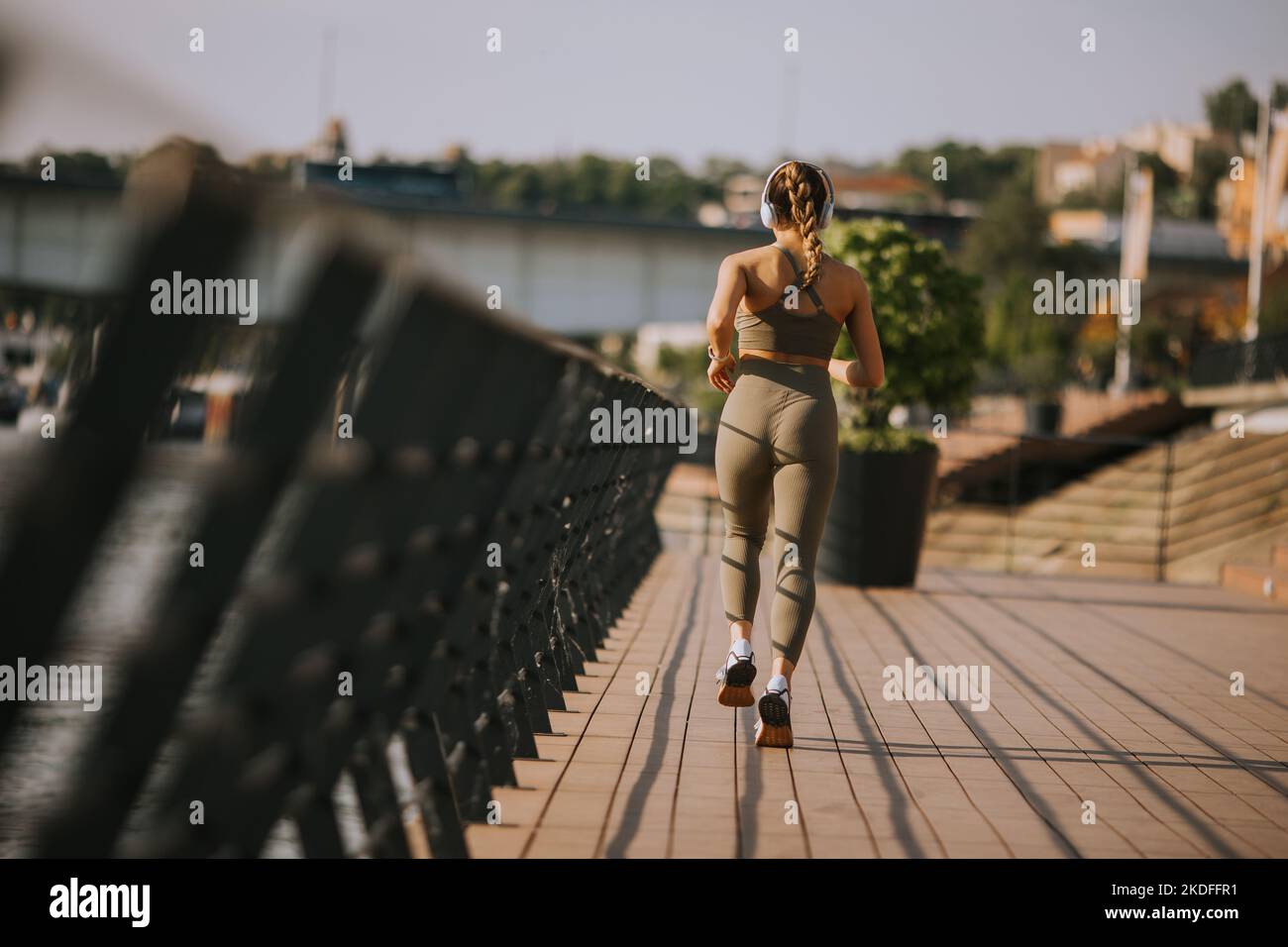 Rear view at active young beautiful woman running on the promenade ...