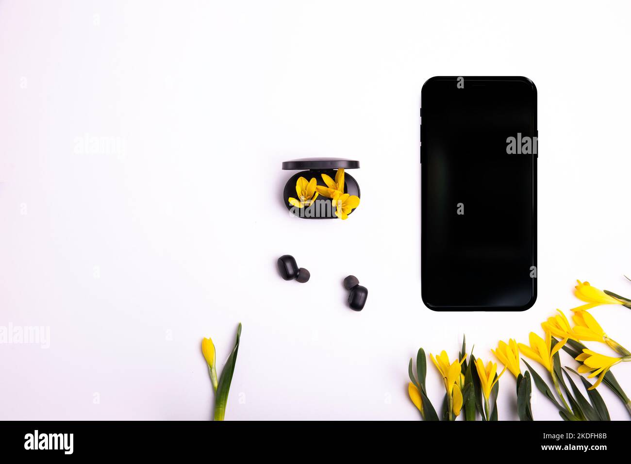 A black smartphone and black wireless earphones isolated on a white ...