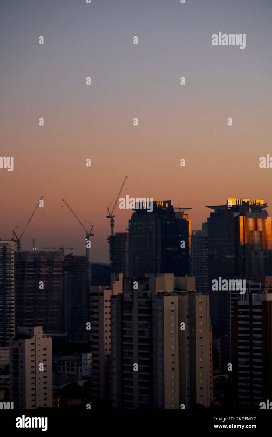 A vertical shot of sunrise behind the tall buildings in the big city ...