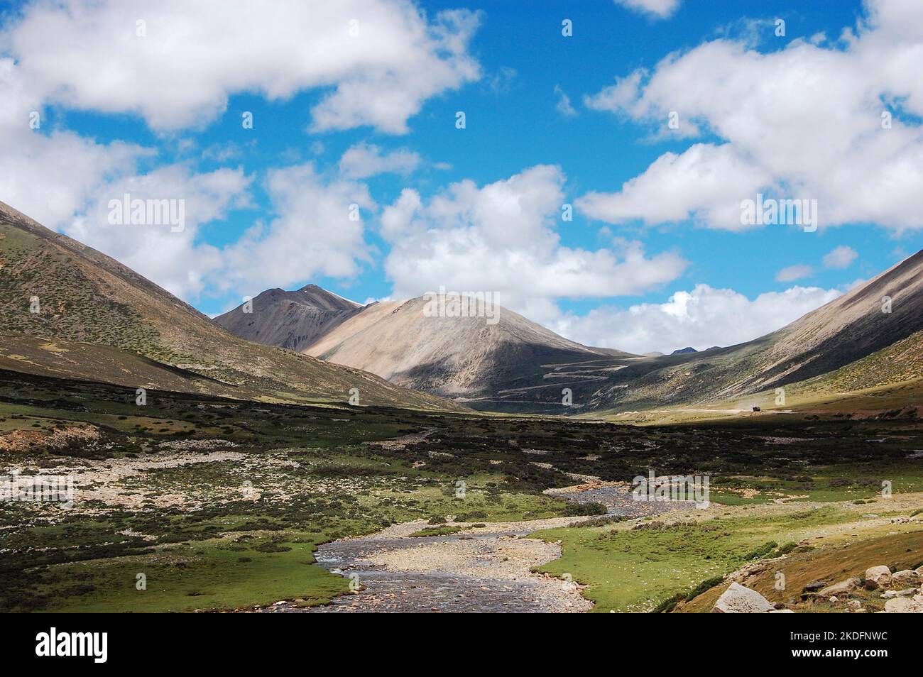 A low-angle of a dusty path leading to the mountains, cloudy sky ...