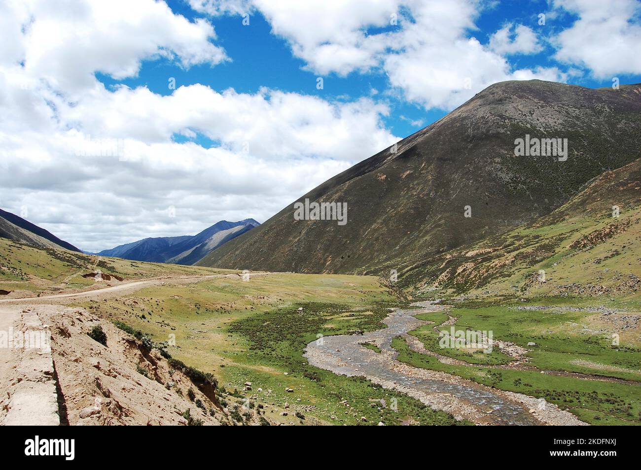 A low-angle of a dusty path leading to the mountains, cloudy sky ...