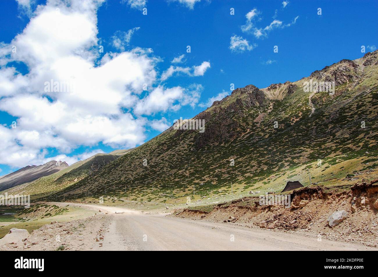 A low-angle of a dusty path leading to the mountains, cloudy sky ...