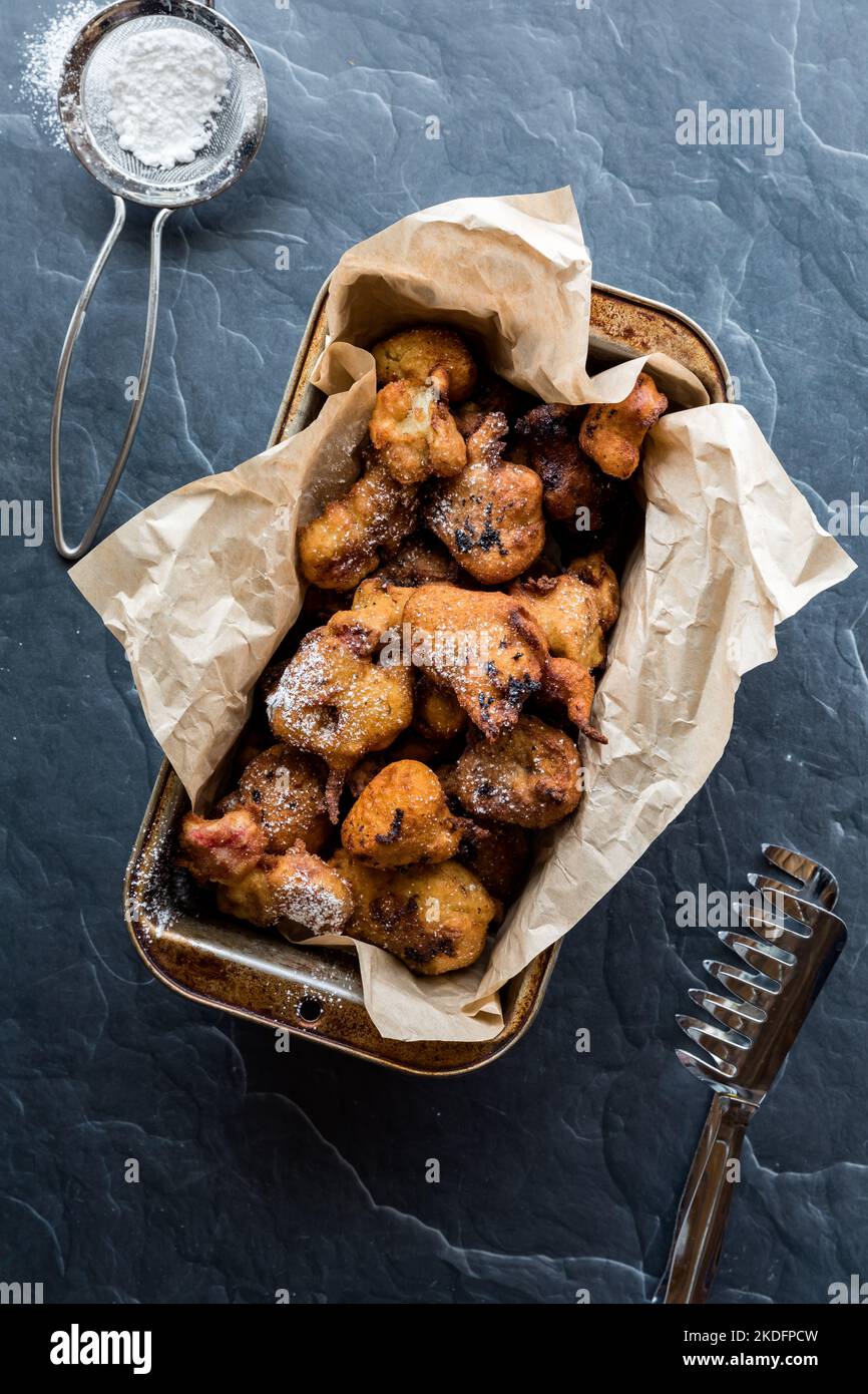 A baking pan lined with parchment paper filled with deep fried fritters ...