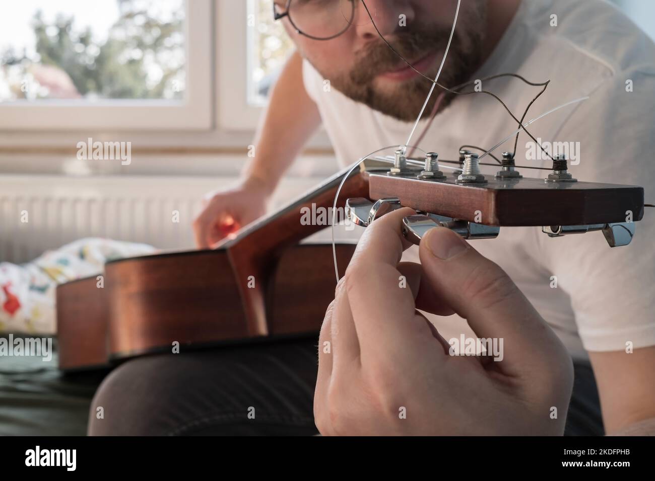Acoustic guitar tuning. Focused man repairs a stringed musical ...